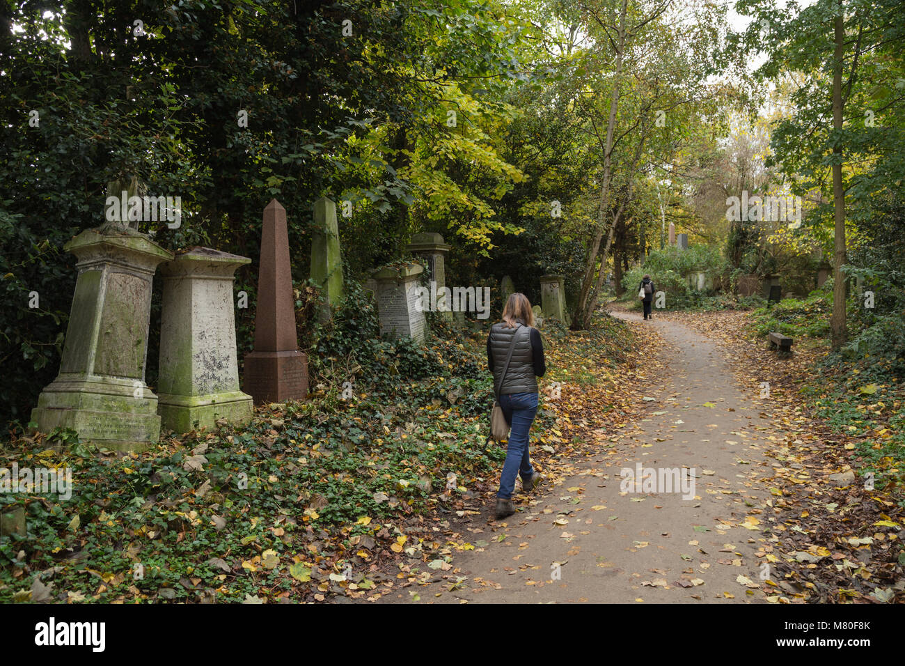 a woman walks along a path between gravestones and tombs in the ...