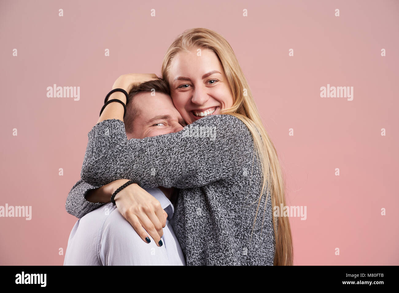 Young woman make big hug to her man isolated on pink background Stock ...