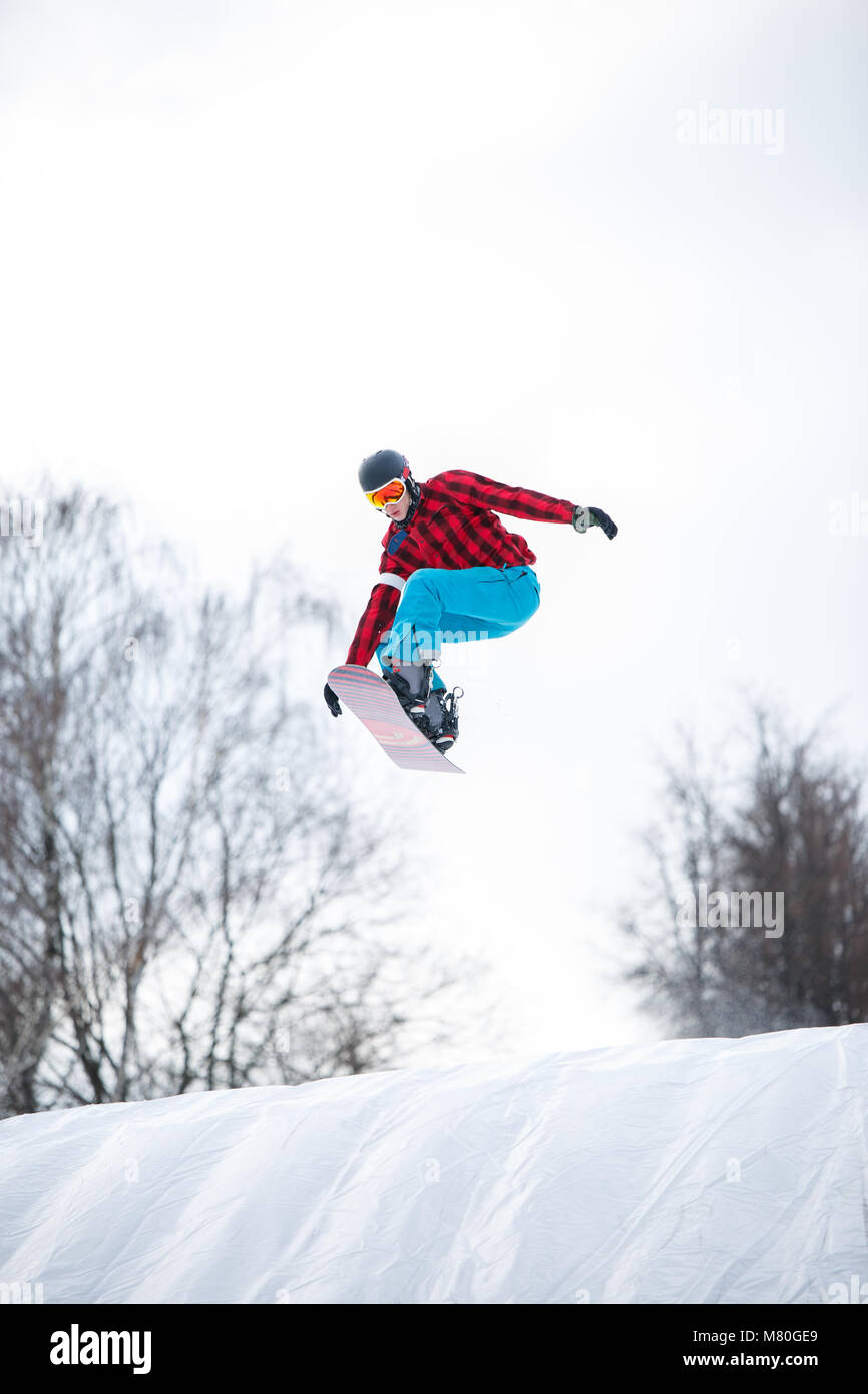 Photo of athlete in helmet riding snowboard from snow slope in winter ...