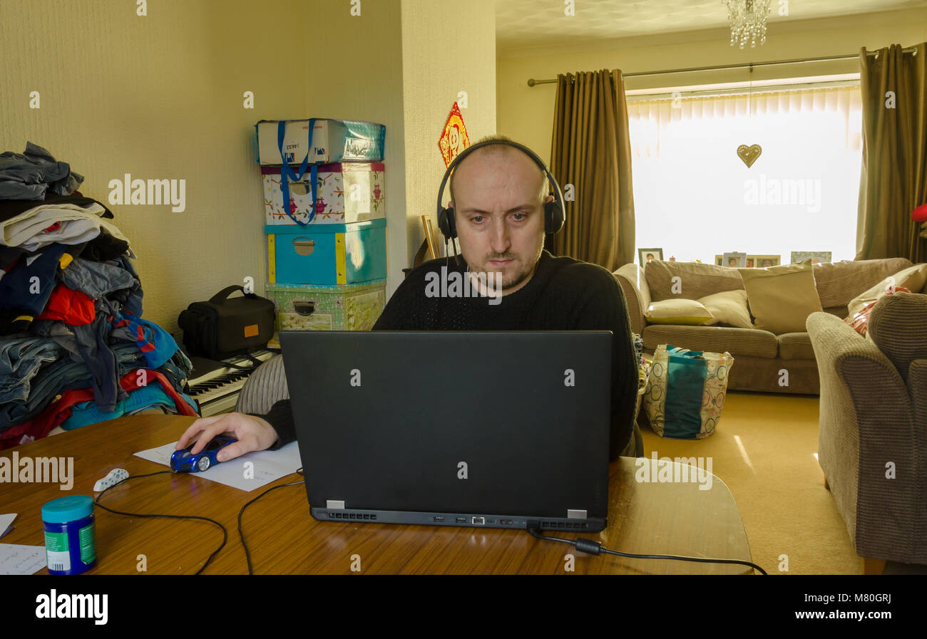 A middle aged man working from home on a laptop computer on the dining ...