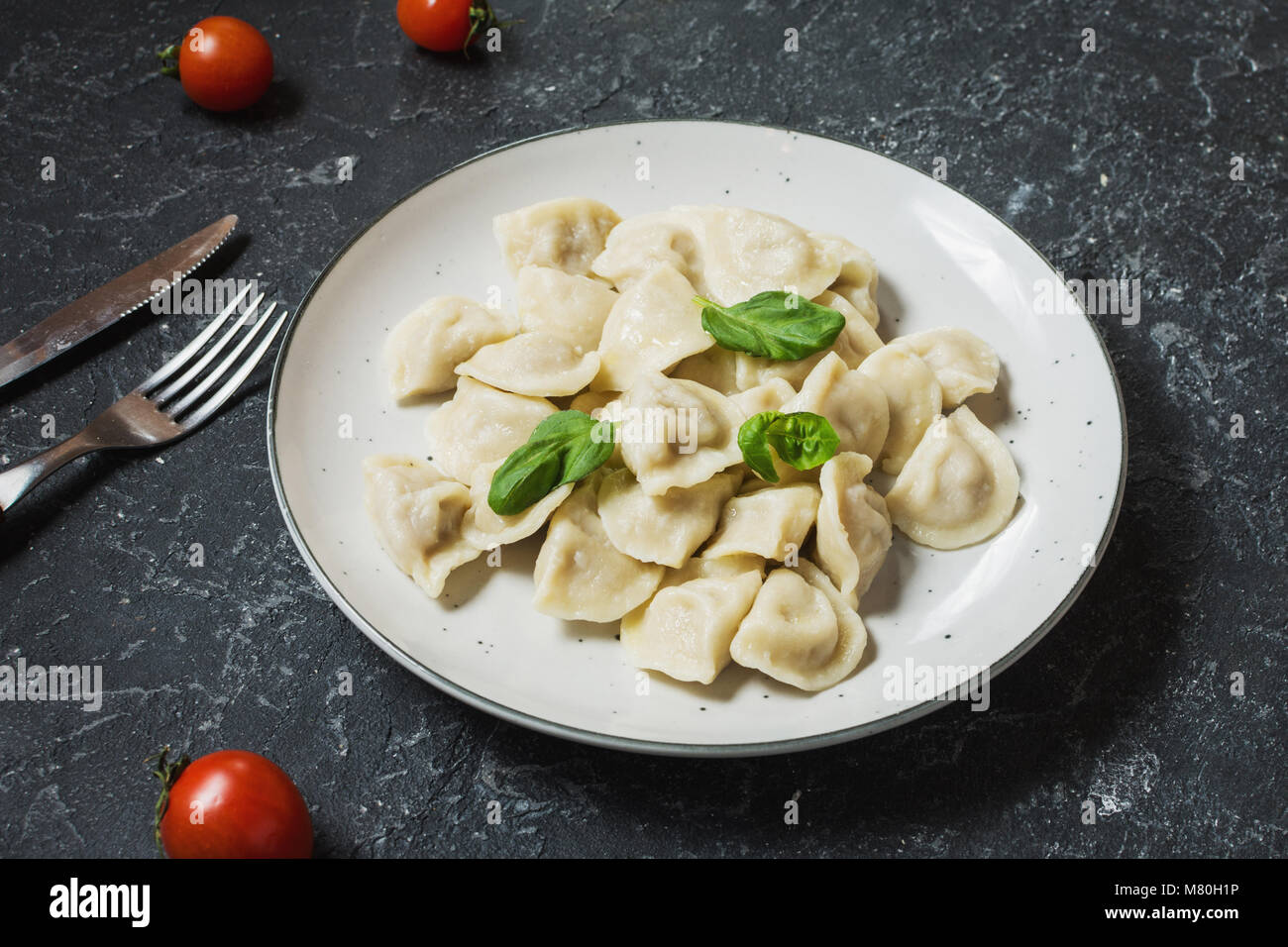 Traditional russian pelmeni, ravioli, dumplings with meat on black ...