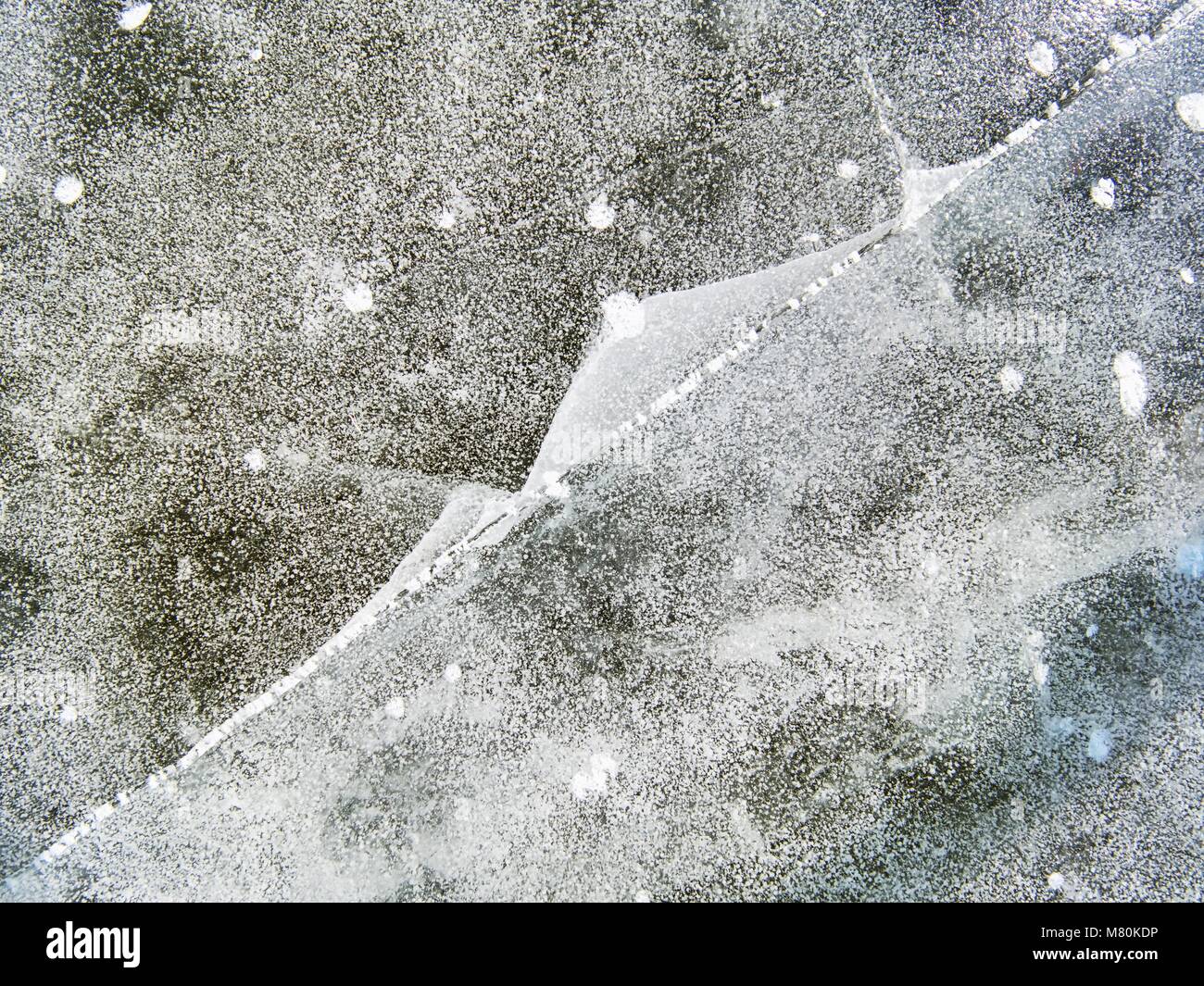 Follow bubbles and crack in the ice on the lake.Reflection of sun rays ...