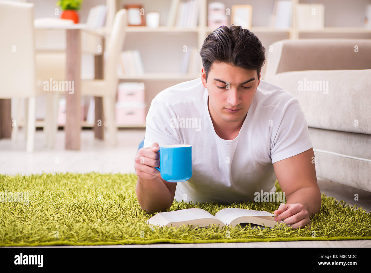 Man reading book at home on floor Stock Photo - Alamy