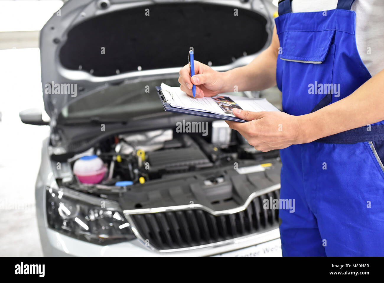 car mechanic in a workshop with checklist - engine repair and diagnosis ...