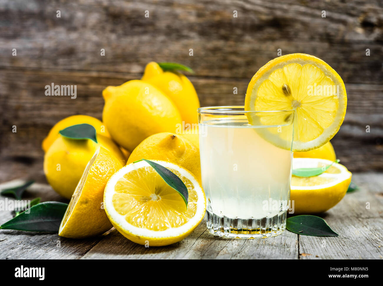 Glass of lemonade and fresh lemons on rustic wooden table Stock Photo ...