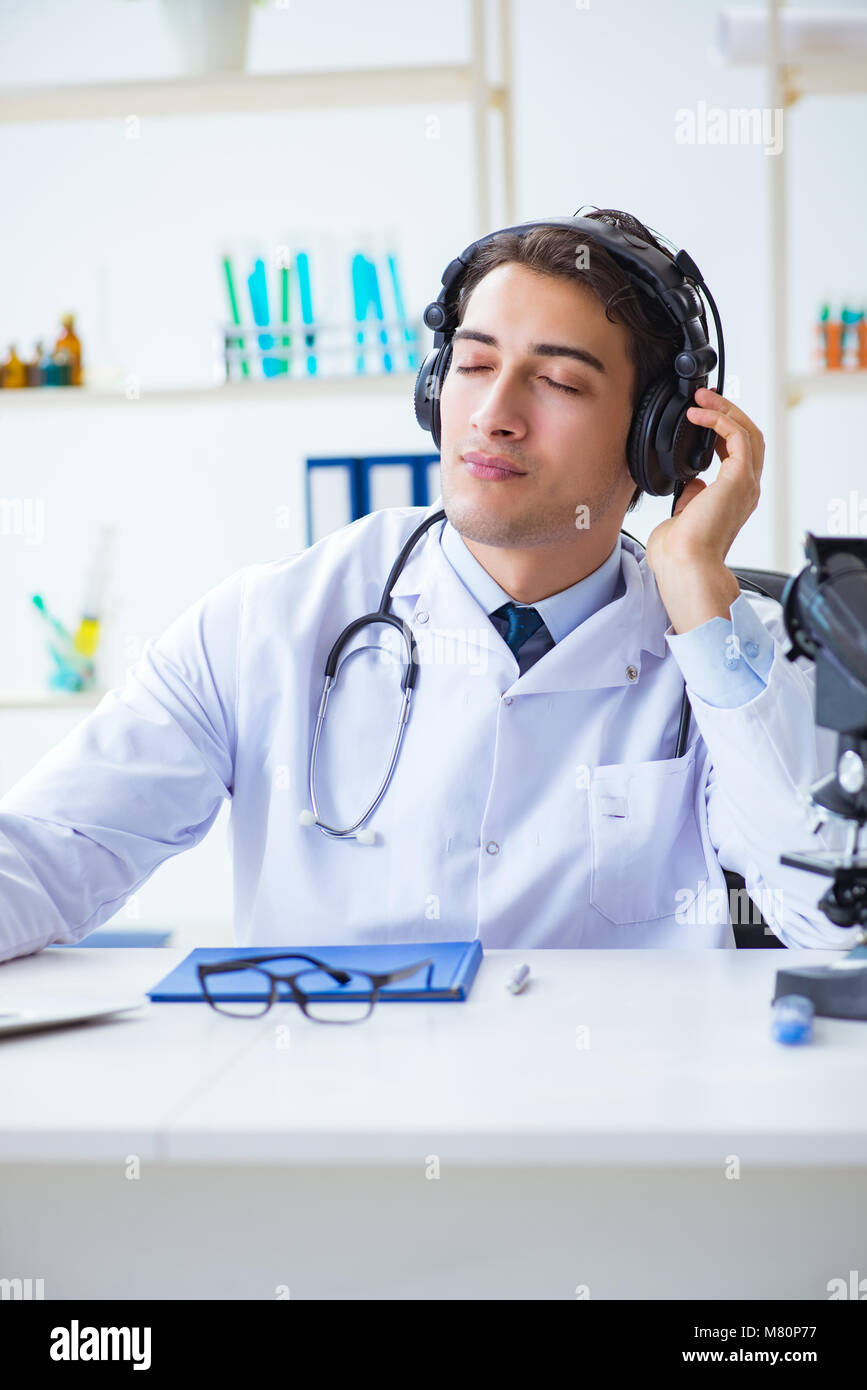 Happy excited doctor listening to music during lunch break in hospital ...