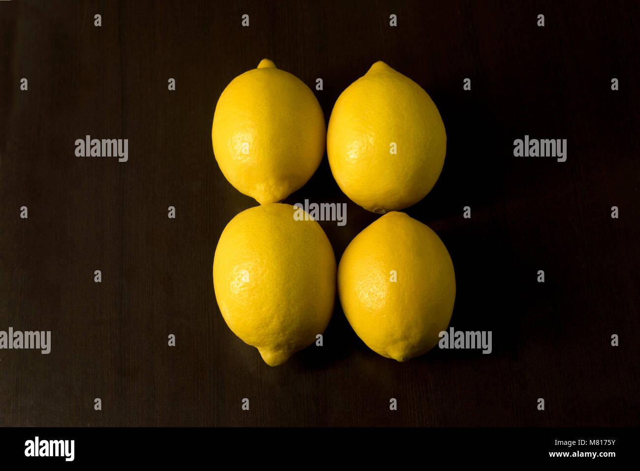 Group of four lemons in a grid- view from above on dark background ...