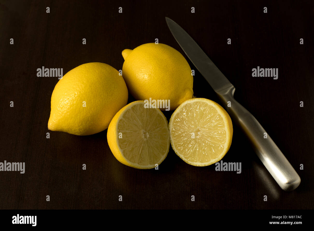 Whole and cut lemons with stainless knife on dark background Stock ...
