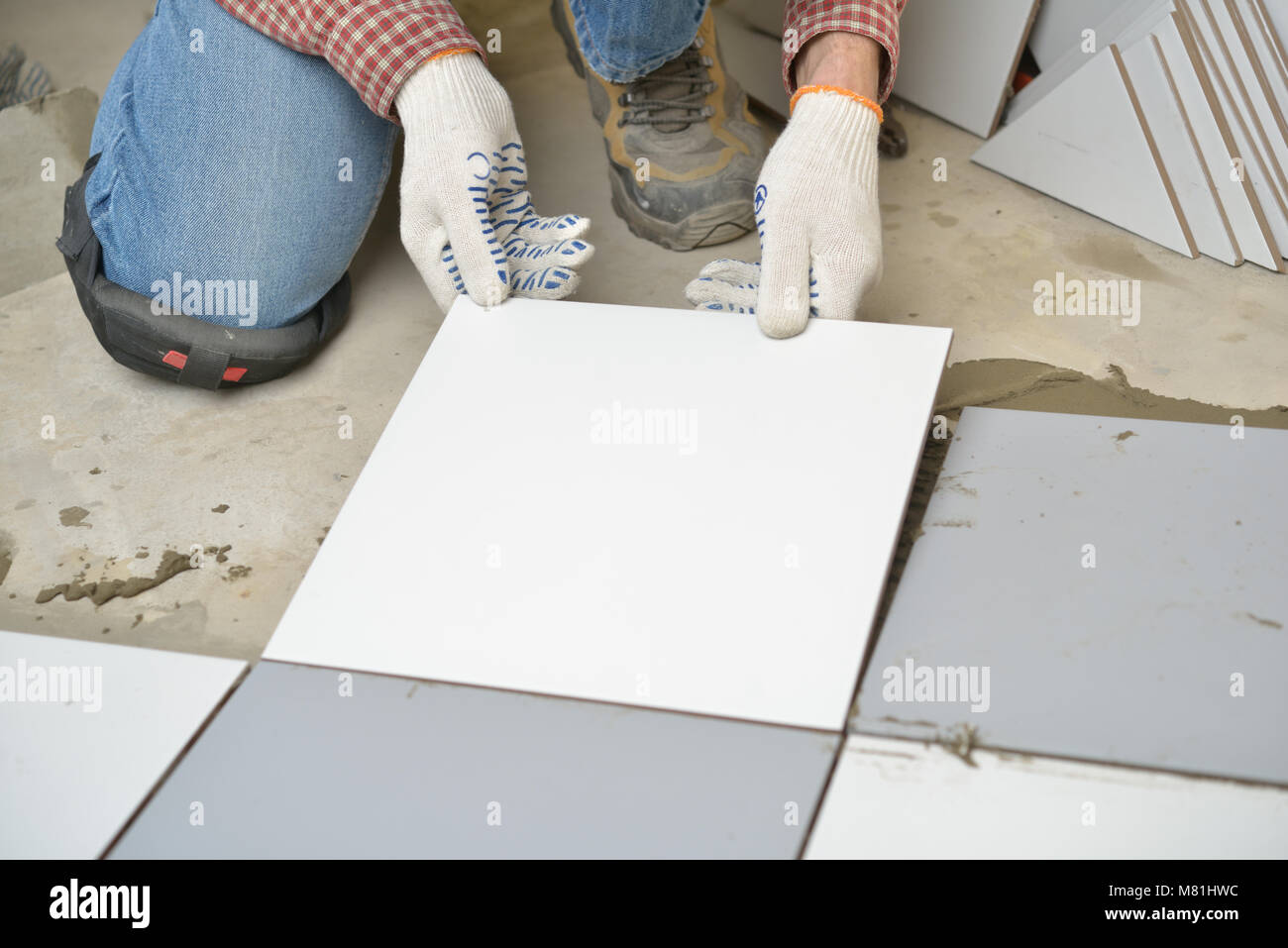 Worker installs ceramic tiles on a floor Stock Photo - Alamy