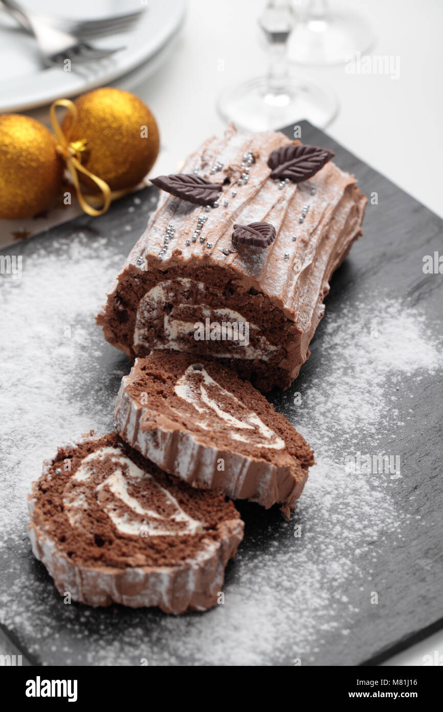 Yule log cake decorated with chocolate leaves on a Christmas table ...