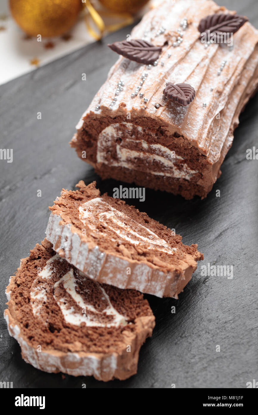 Yule log cake decorated with chocolate leaves on a Christmas table ...