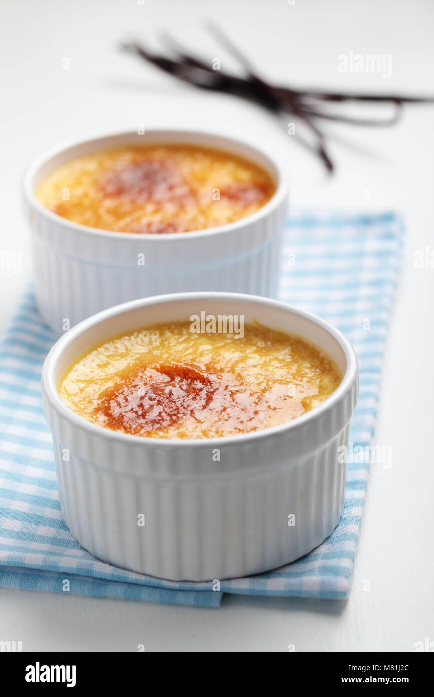 Two portions of vanilla creme brulee in ramekins Stock Photo - Alamy
