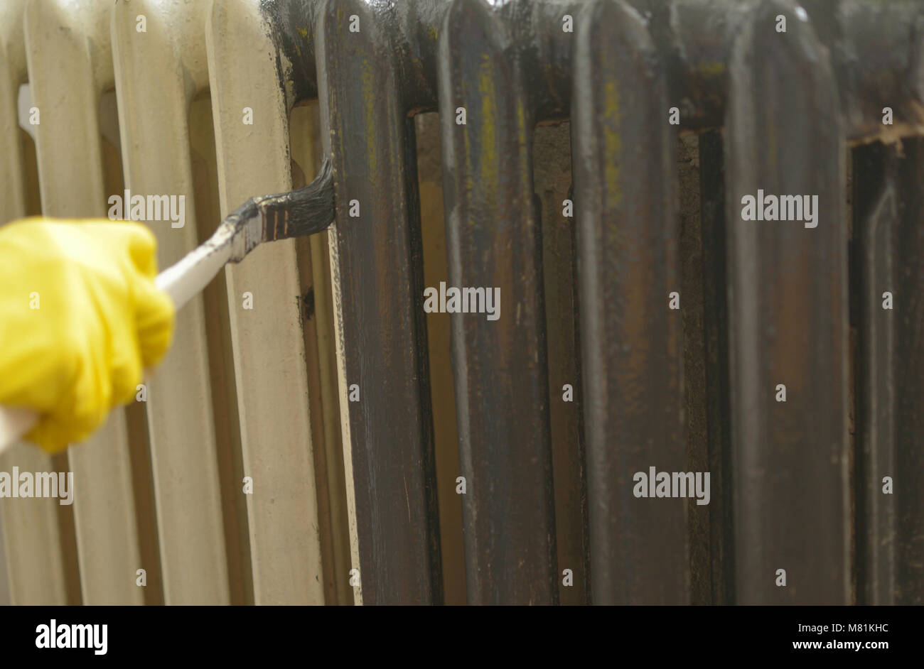 Painting a cast-iron radiator in dark gray Stock Photo - Alamy