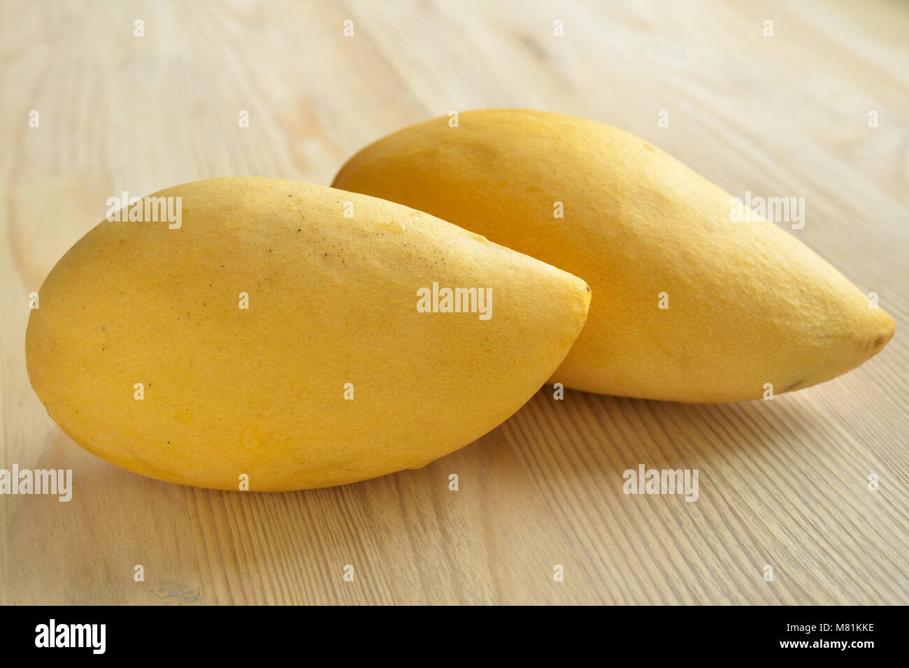 Two Thai mangoes on a wooden table Stock Photo - Alamy