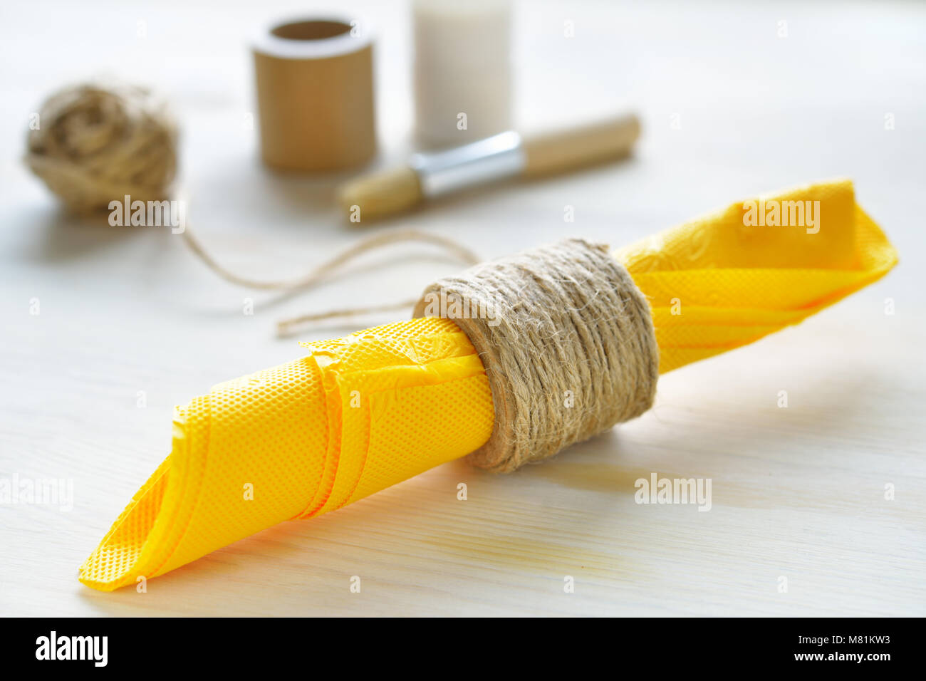 Yellow napkins in a rope DIY serviette ring Stock Photo - Alamy