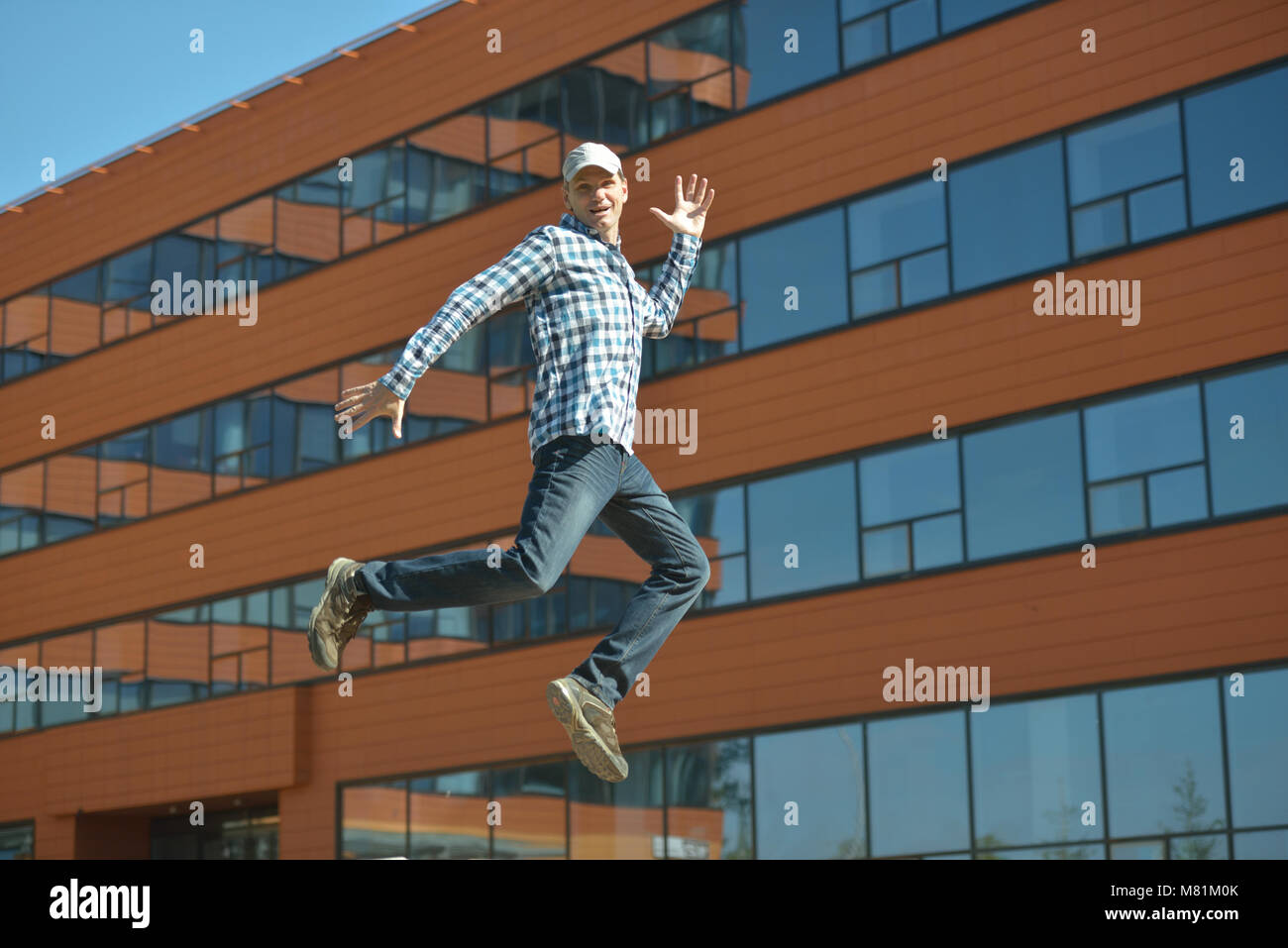 Jumping man against modern building Stock Photo - Alamy