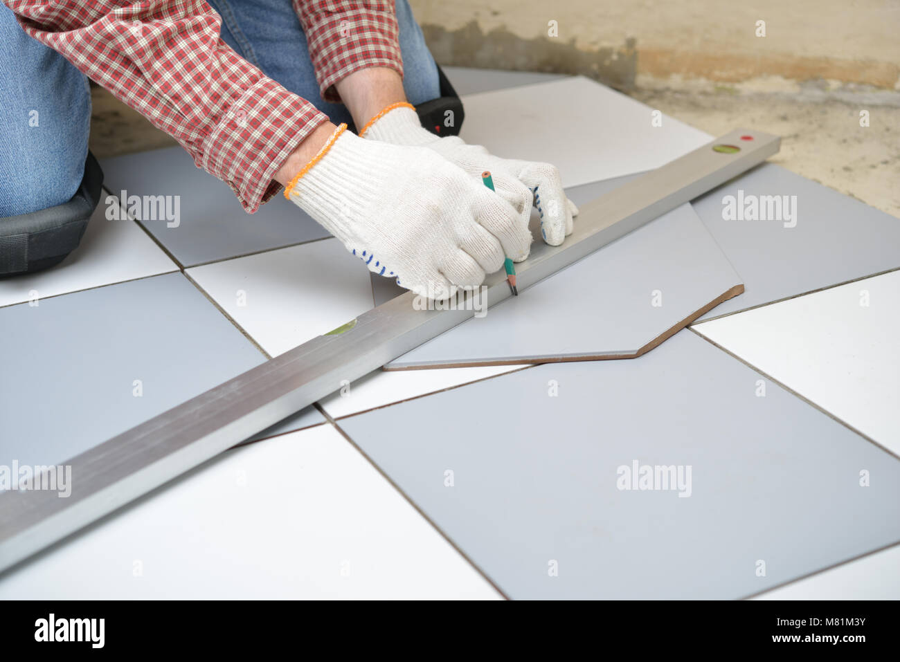 Tiler marks the tile during the floor installation Stock Photo - Alamy