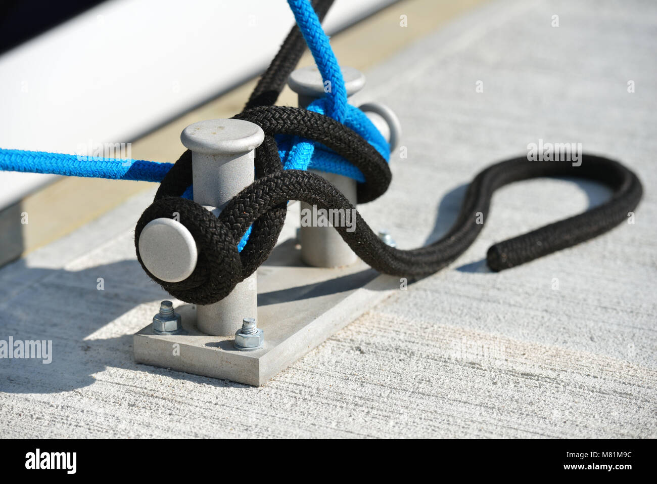 Double bollard with ropes on the pier Stock Photo - Alamy