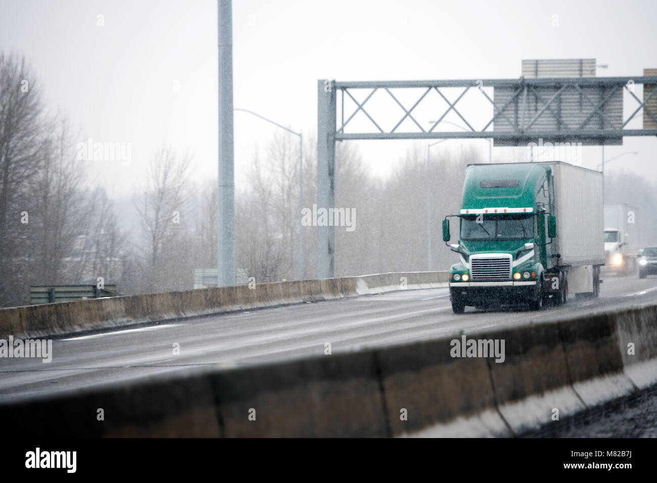 Big rig green American semi truck with dry van semi trailer driving on ...