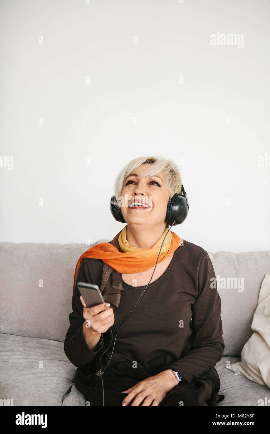 Elderly woman listening to music and smiling. The older generation and ...