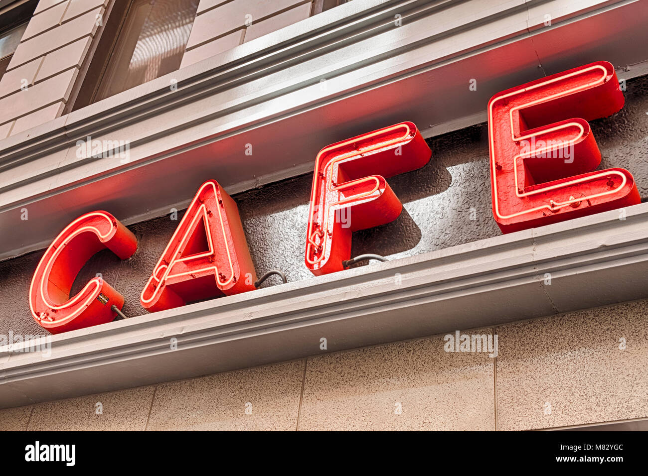 A bright red neon sign advertising a cafe lights up the wall over a ...