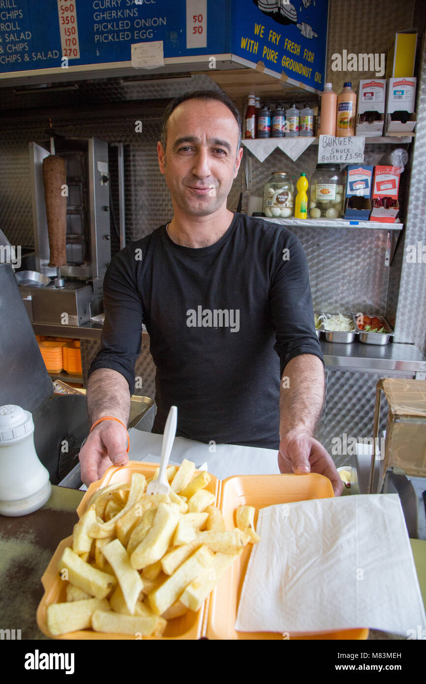 Man serving chips at a takeaway fish and chips restaurant Stock Photo ...