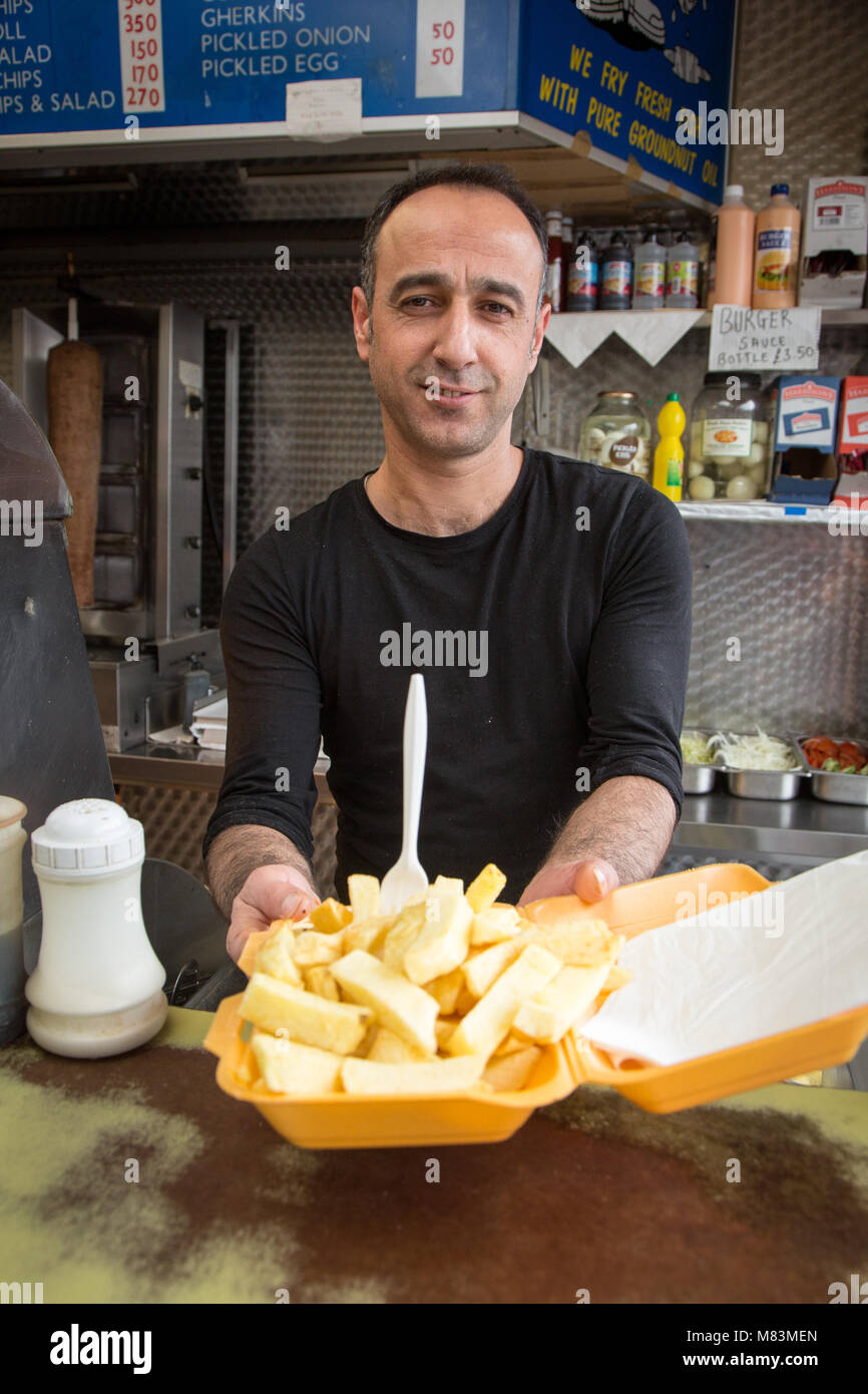 Man serving chips at a takeaway fish and chips restaurant Stock Photo ...
