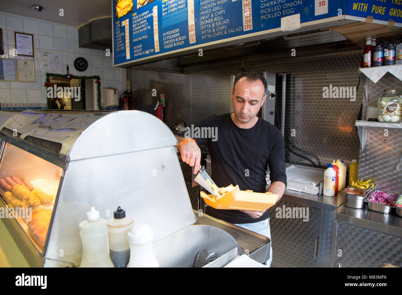 Man serving chips at a takeaway fish and chips restaurant Stock Photo ...