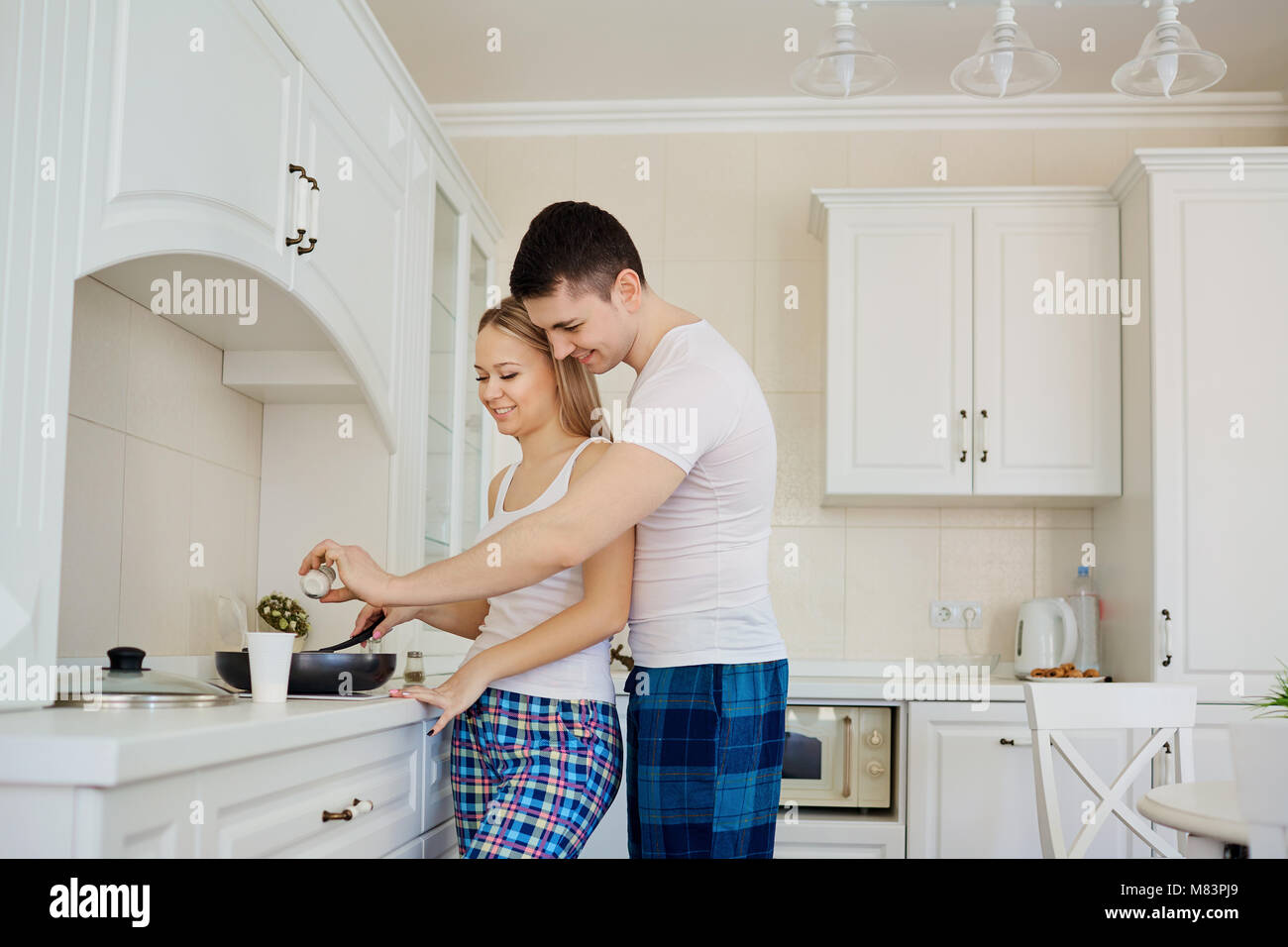 A couple in their pajamas is cooking food in the kitchen Stock Photo ...