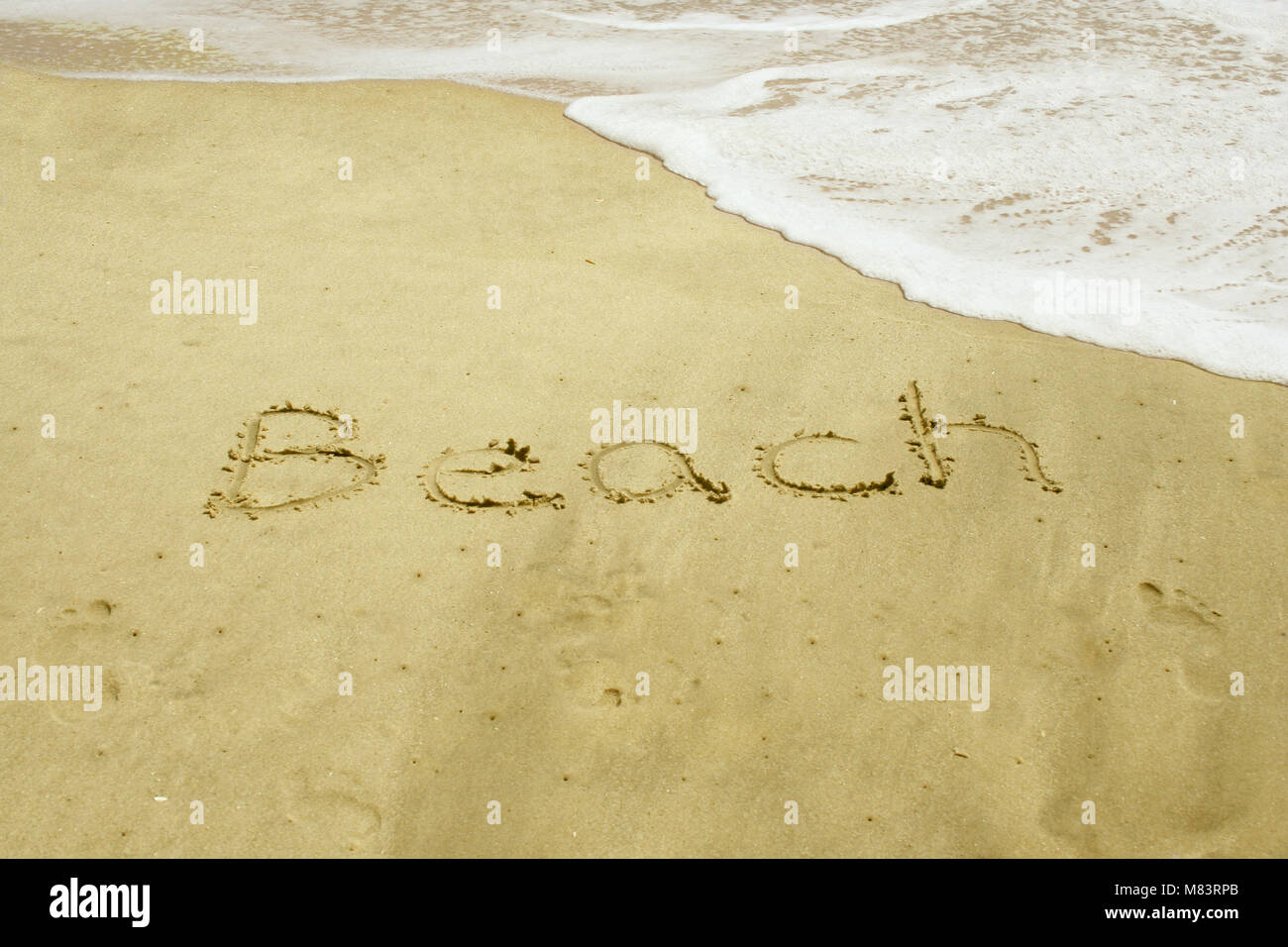 The word Beach written in sand with water Stock Photo - Alamy