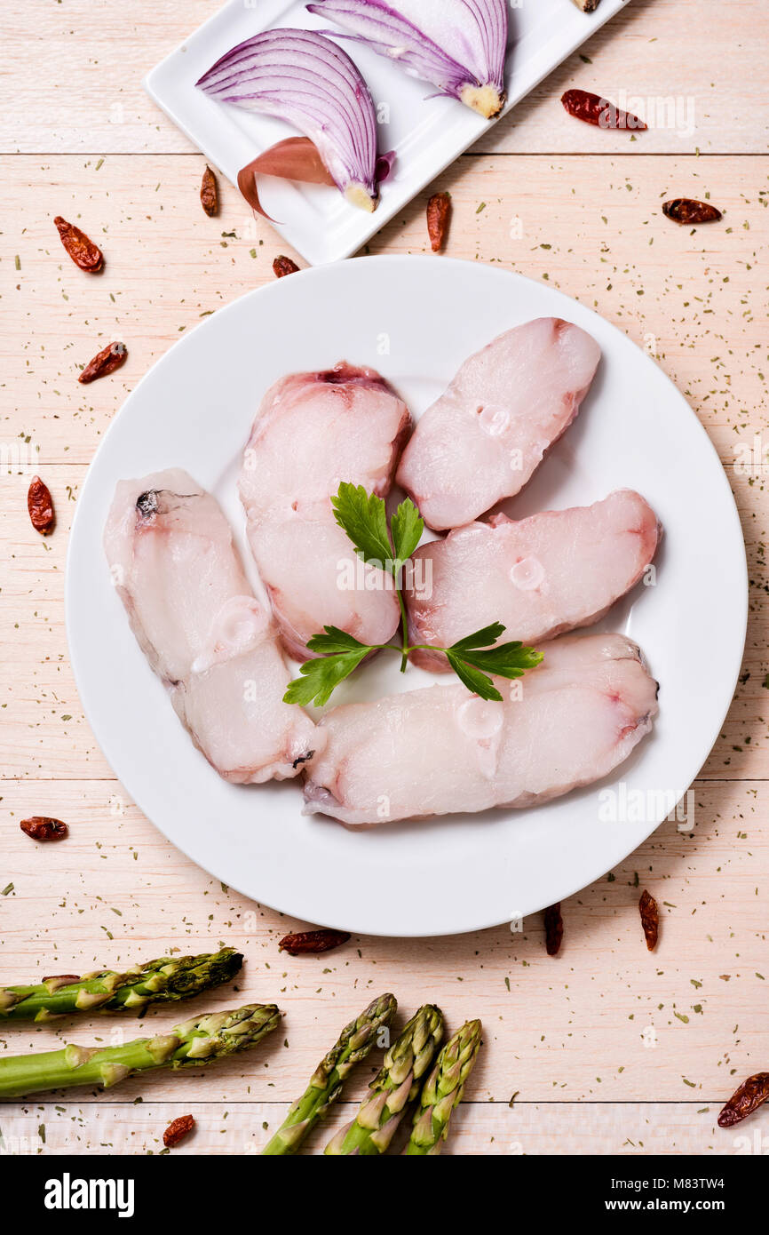 high angle view of some slices of raw monkfish on a white ceramic plate ...