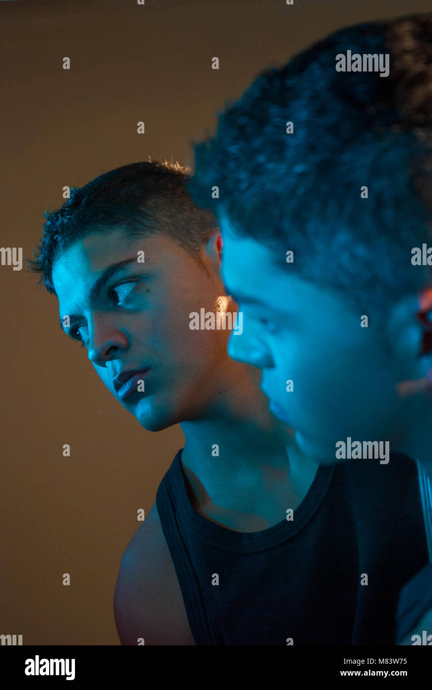 Young man and its reflection on mirror. Blue light Stock Photo - Alamy