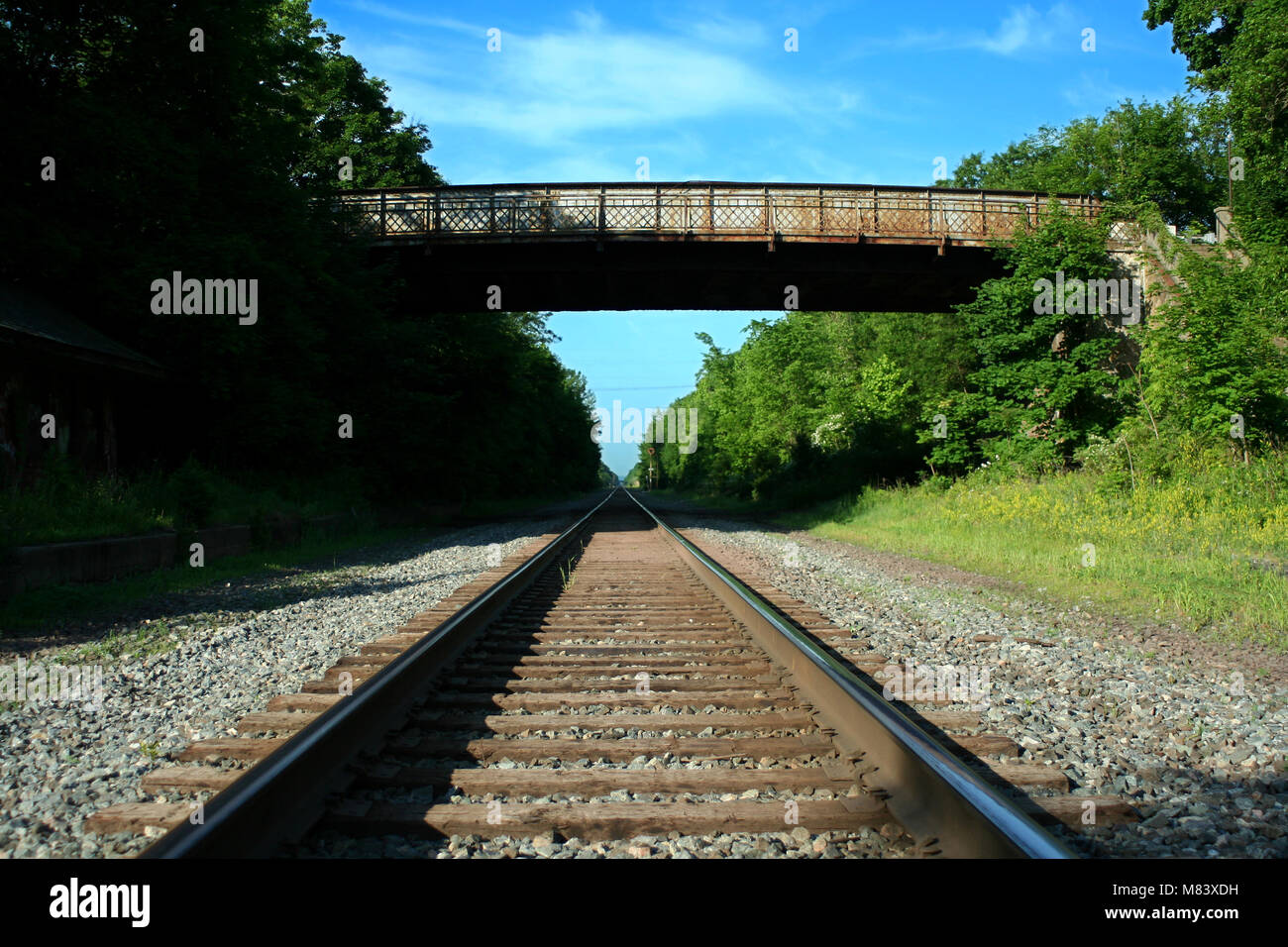 Looking down Railroad tracks with bridge and sky Stock Photo - Alamy