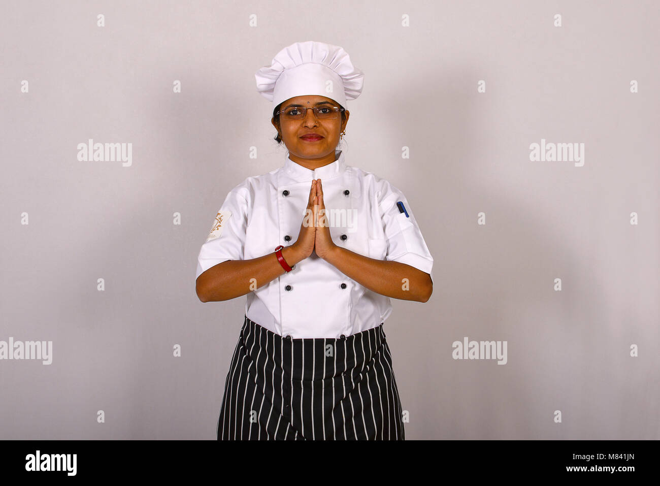 Female chef in a restaurant standing with Namaste greeting Stock Photo ...
