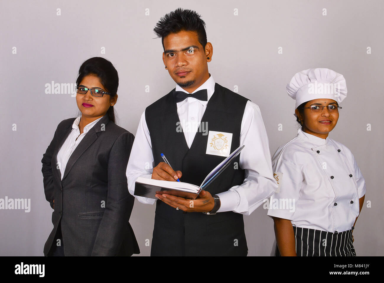 Restaurant server with notebook and staff behind Stock Photo - Alamy