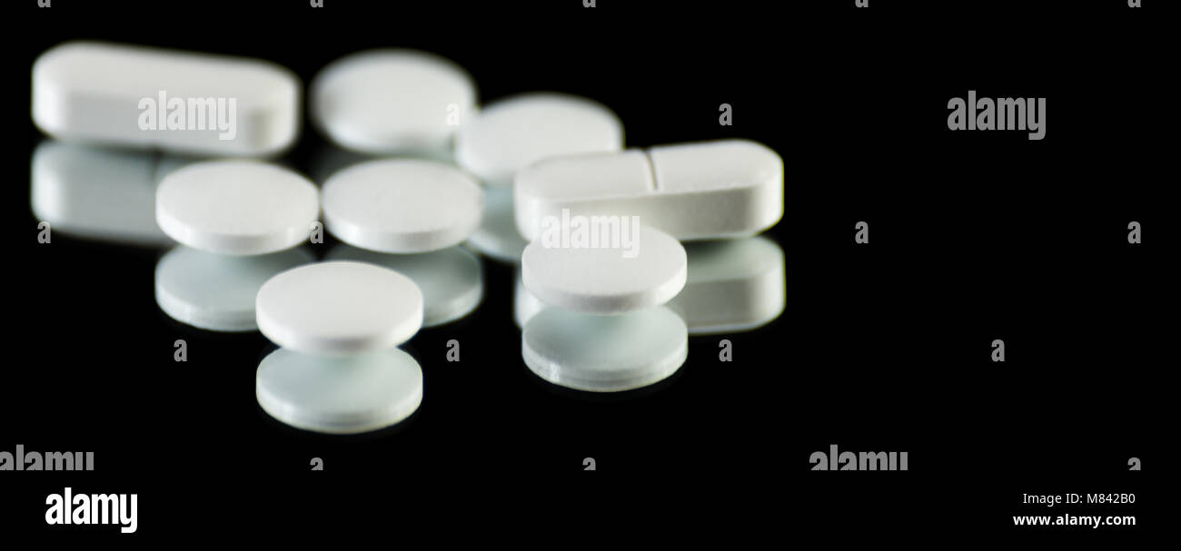 scattered tablets on a black background, pills reflected in the mirror ...
