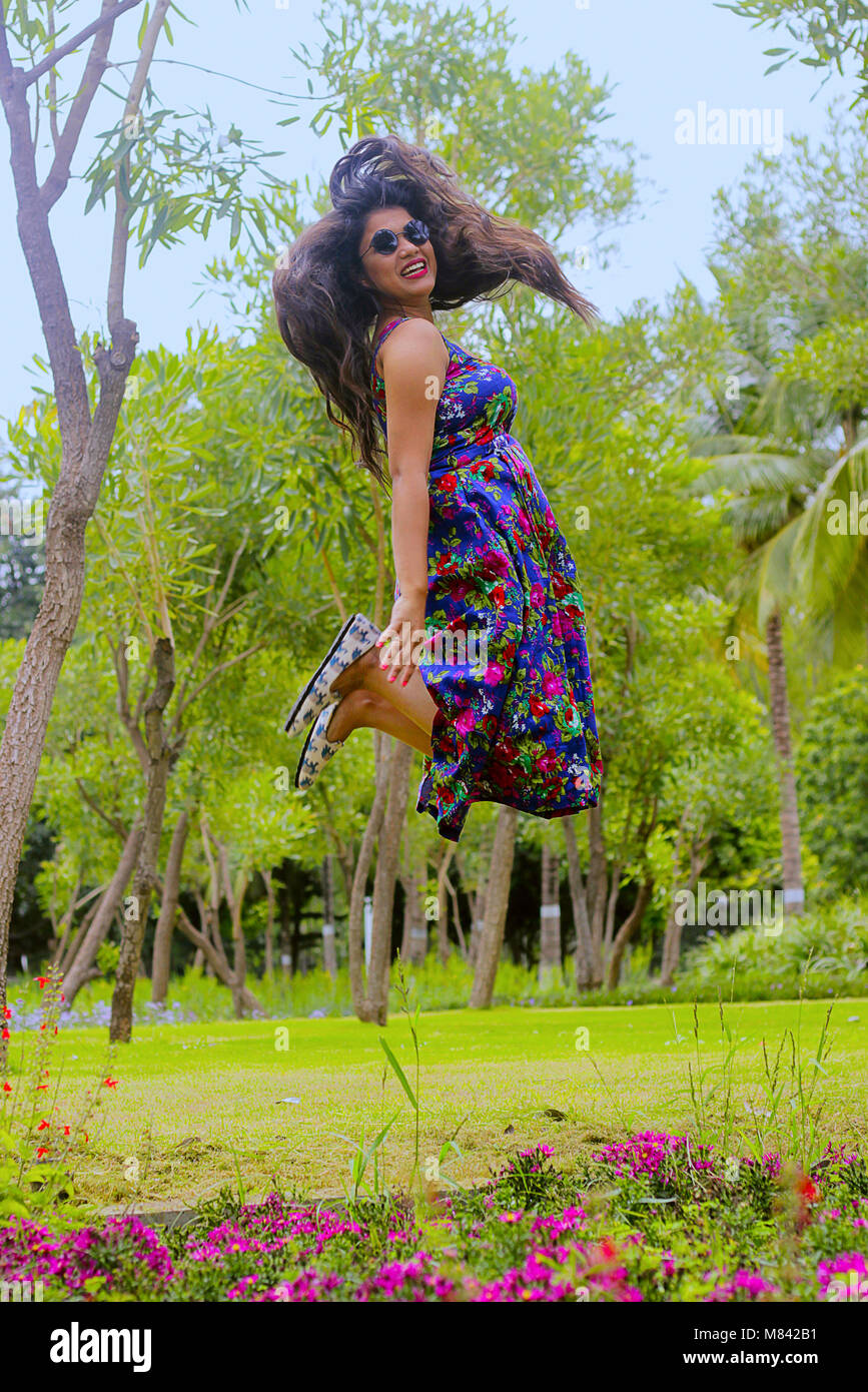 Girl with floral dress in garden jumping in air Stock Photo - Alamy