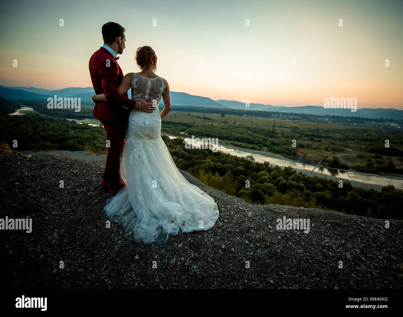 Back view of the beautiful fashionable newlywed couple hugging while ...