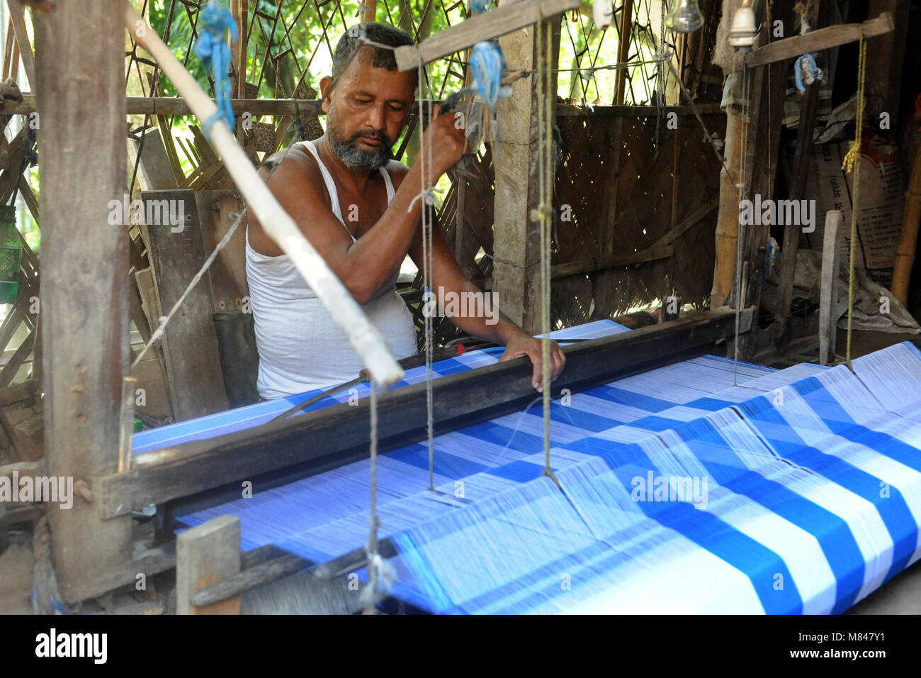 DHAKA, BANGLADESH - AUGUST 29, 2016: A worker weaves cloth at a ...
