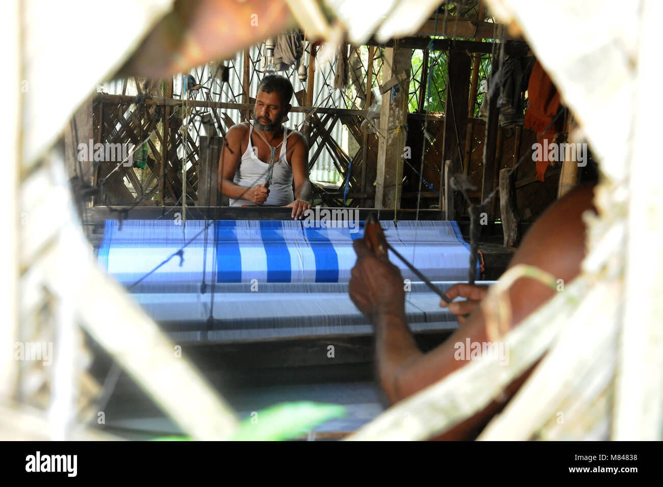 DHAKA, BANGLADESH - AUGUST 29, 2016: A worker weaves cloth at a ...