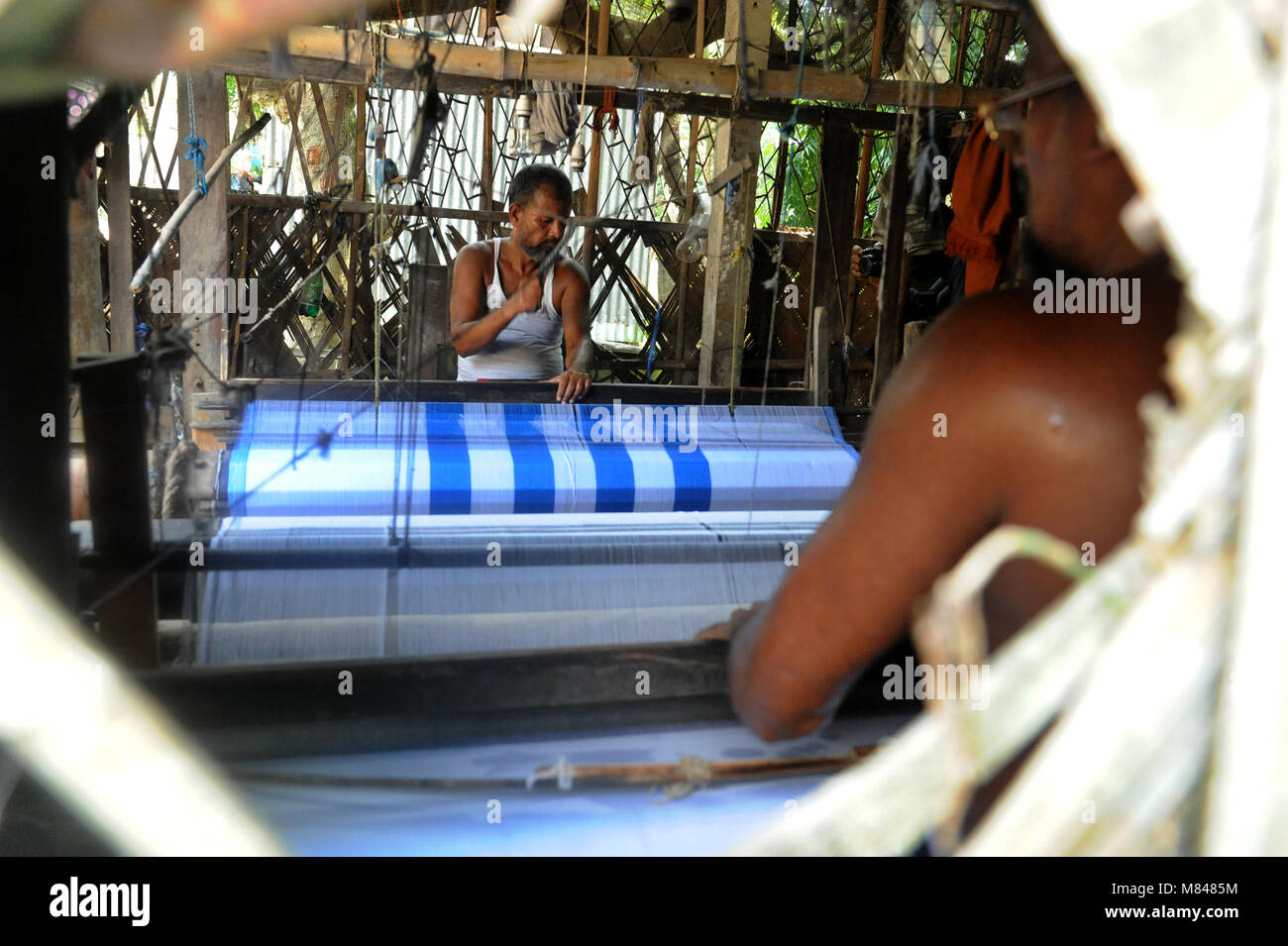 DHAKA, BANGLADESH - AUGUST 29, 2016: A worker weaves cloth at a ...