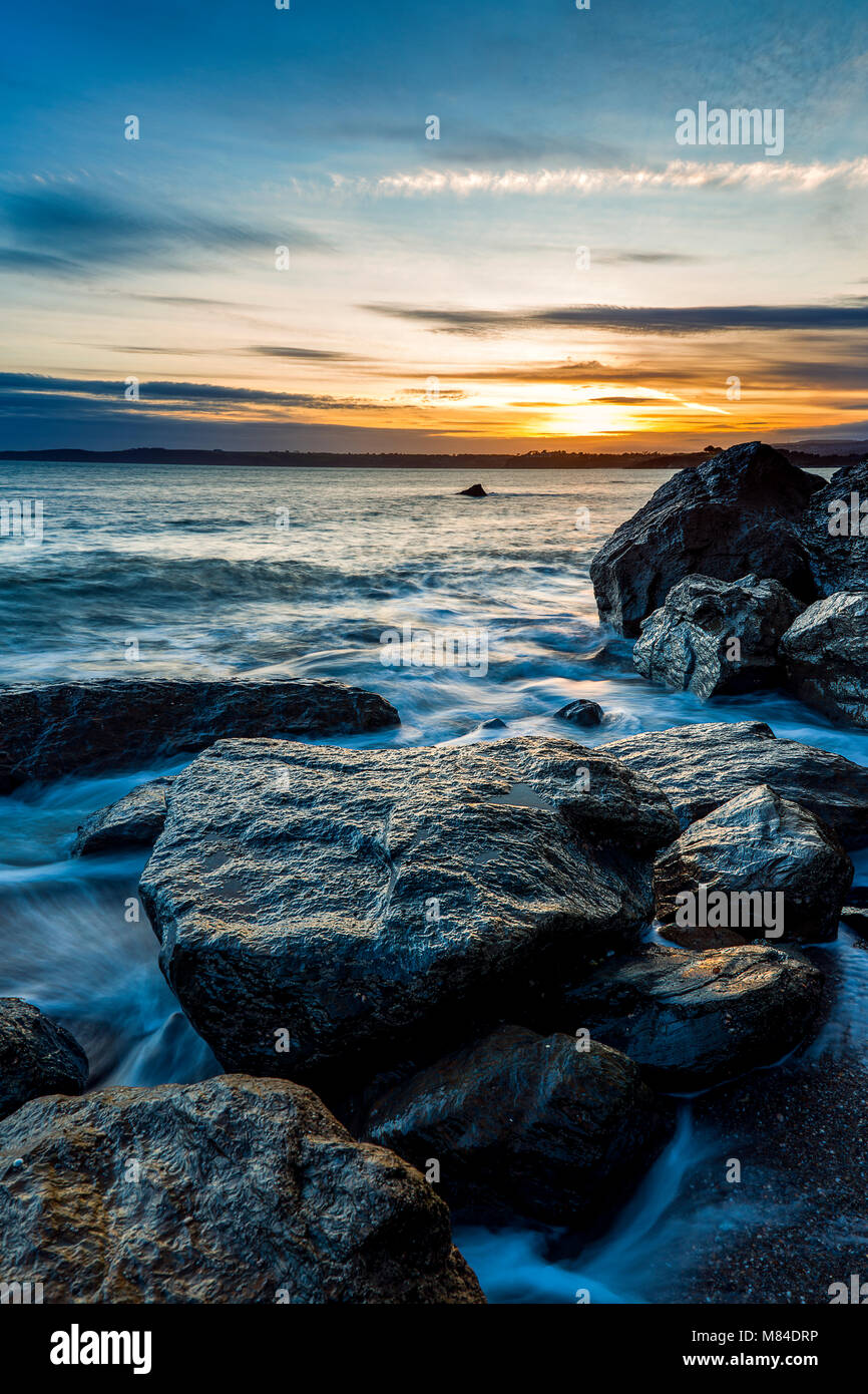 Sunset closes the day over the huge boulders at Polerris Beach in ...