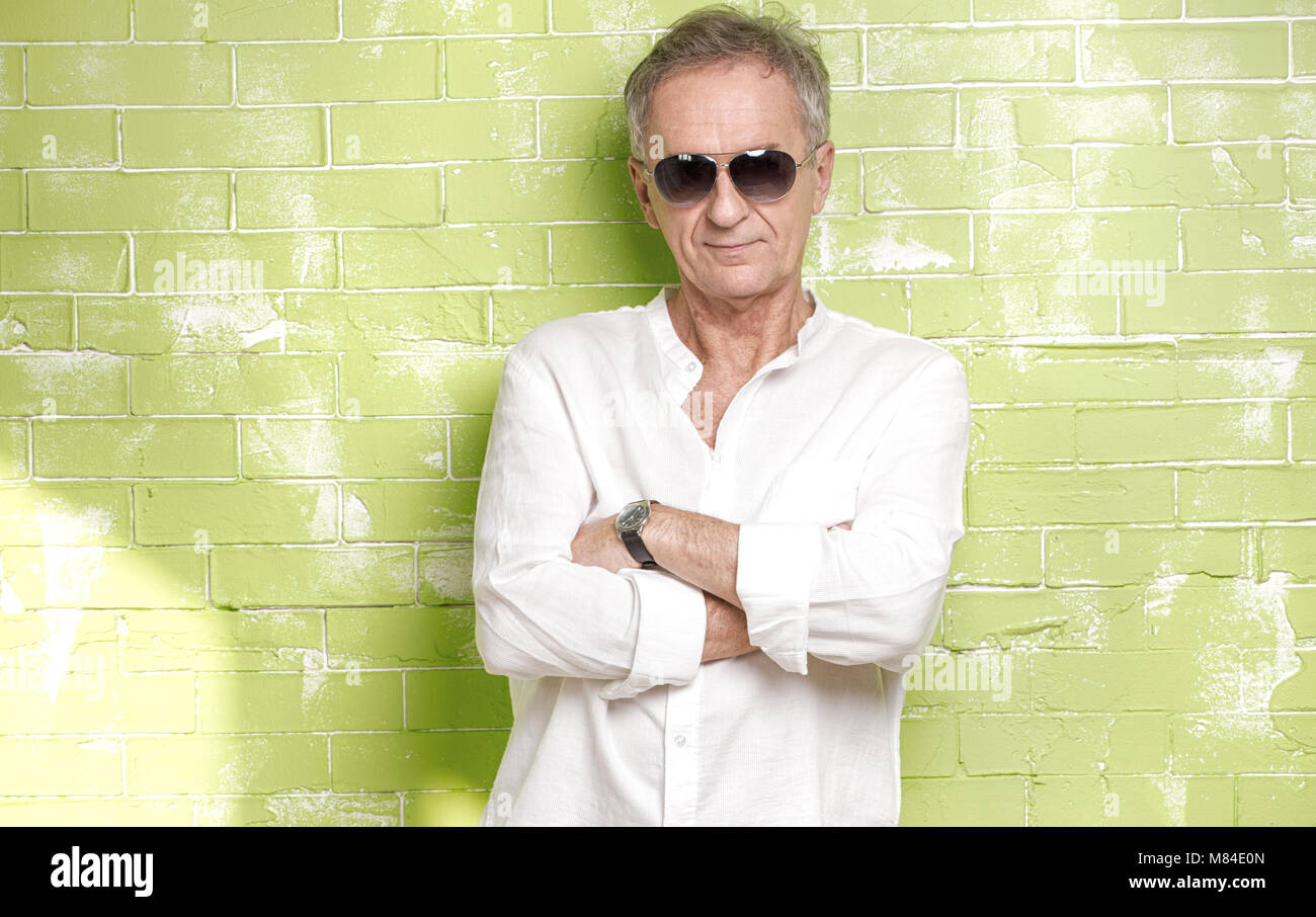 Fashionable handsome senior man posing in studio on green wall Stock ...