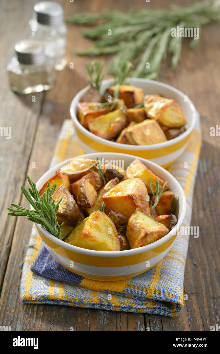 Roasted potatoes with rosemary on a rustic table Stock Photo - Alamy