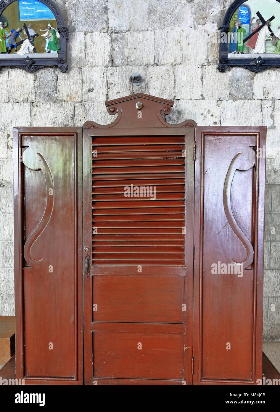 Confessional box made of polished wood under stations III and IV of the ...