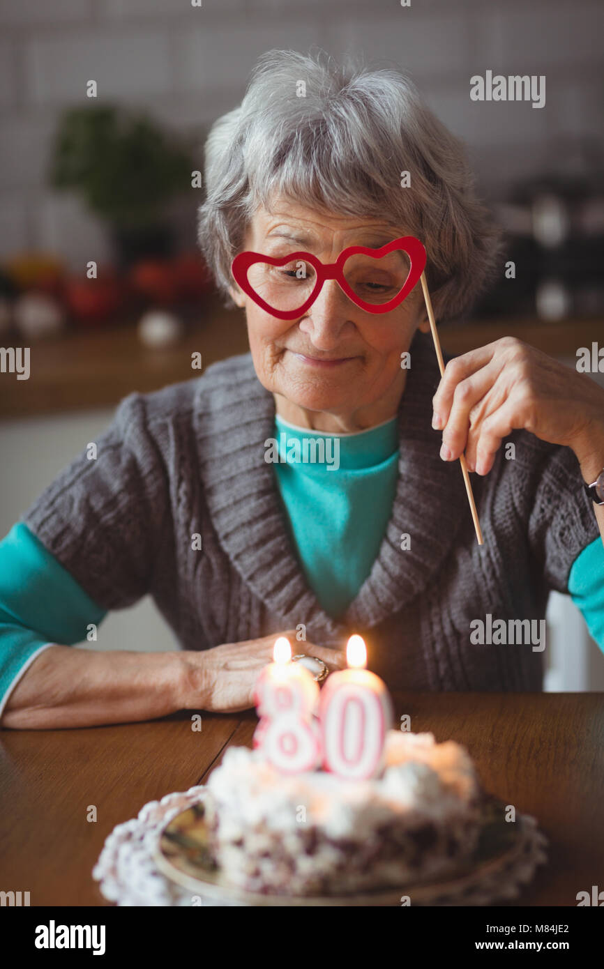Senior woman with birthday cake holding masquerade mask Stock Photo - Alamy