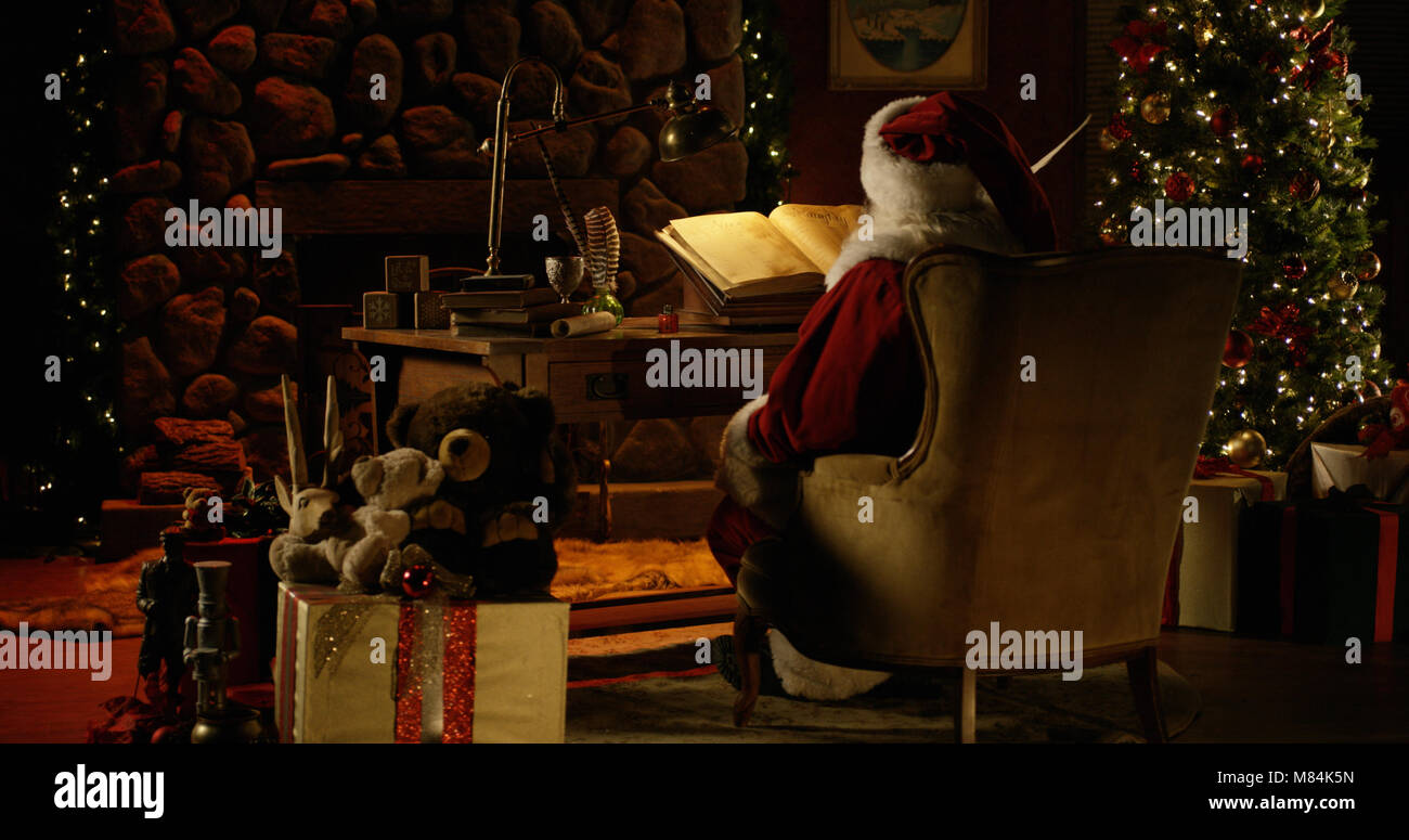Santa Claus works at his desk, surrounded by Christmas decorations ...