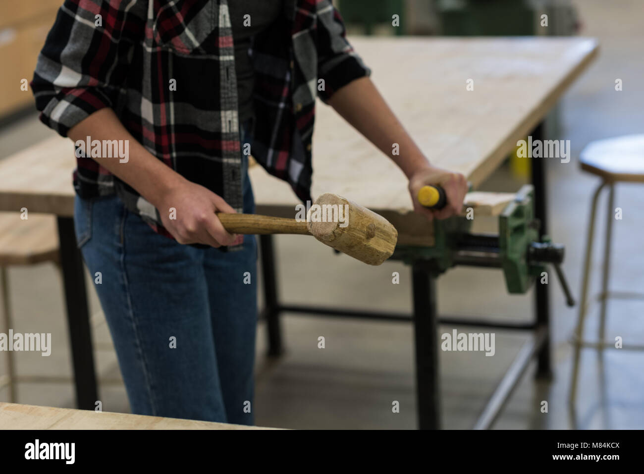 Female carpenter using chisel with hammer on a piece of wood at ...