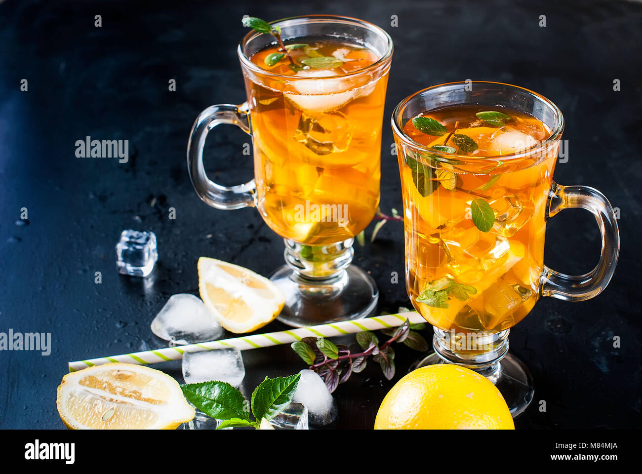 Glasses of iced tea with lemon slices on black background Refreshing ...
