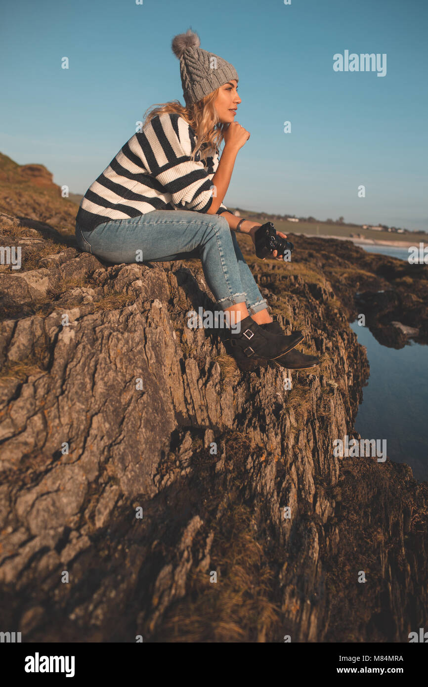 Woman sitting on rock at beach Stock Photo - Alamy